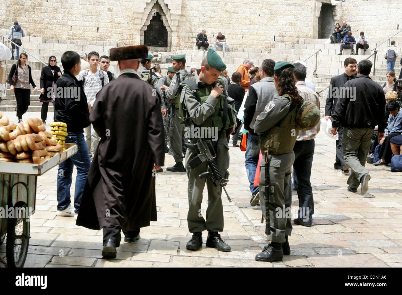 Palestinians walk past an Israeli police officers as they stand guards ...