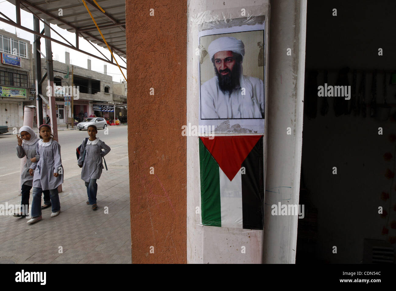 Palestinians walk past a poster of Osama bin Laden, in the southern ...