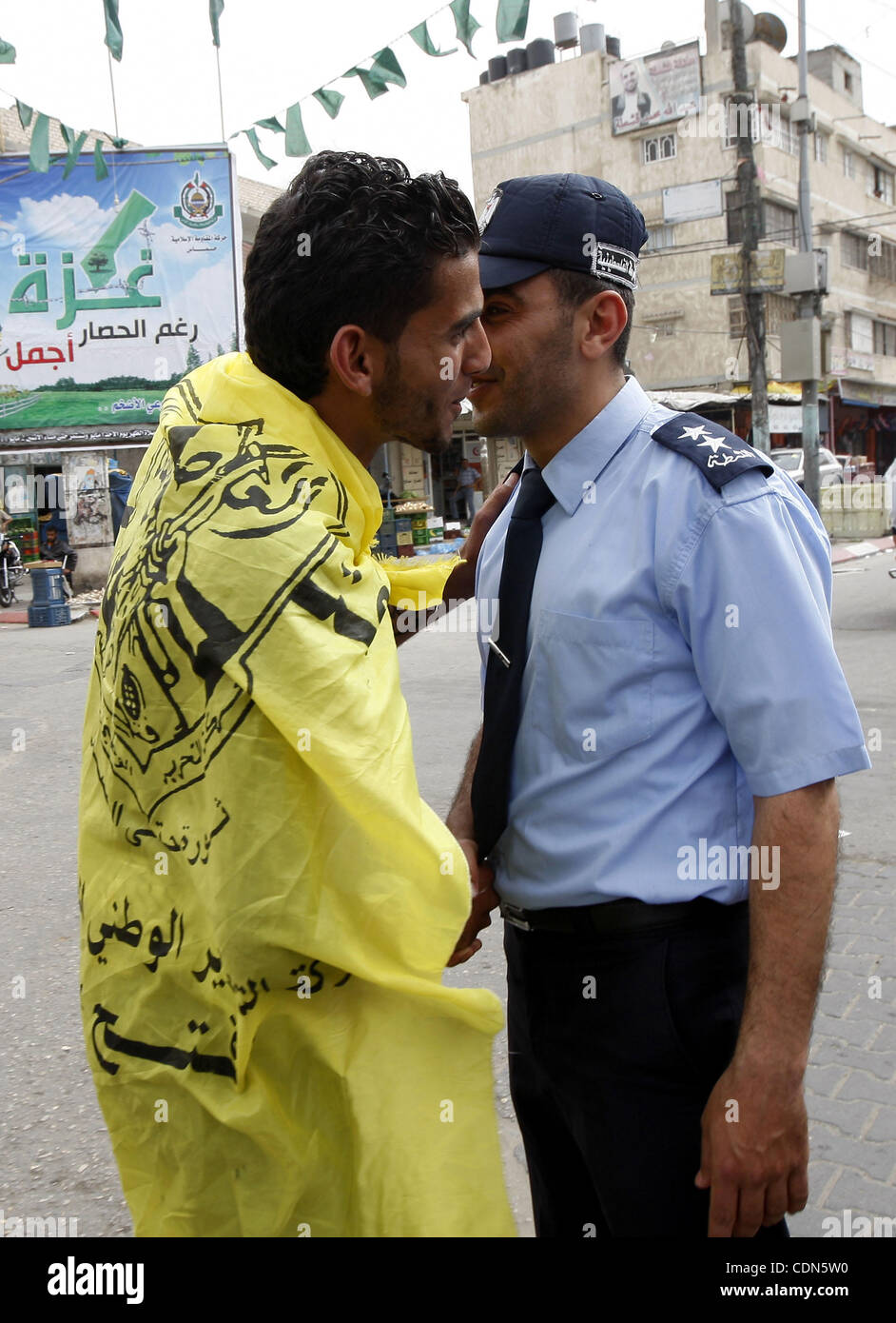 A Palestinian man wrapped with the Fatah party flag shakes hands and ...