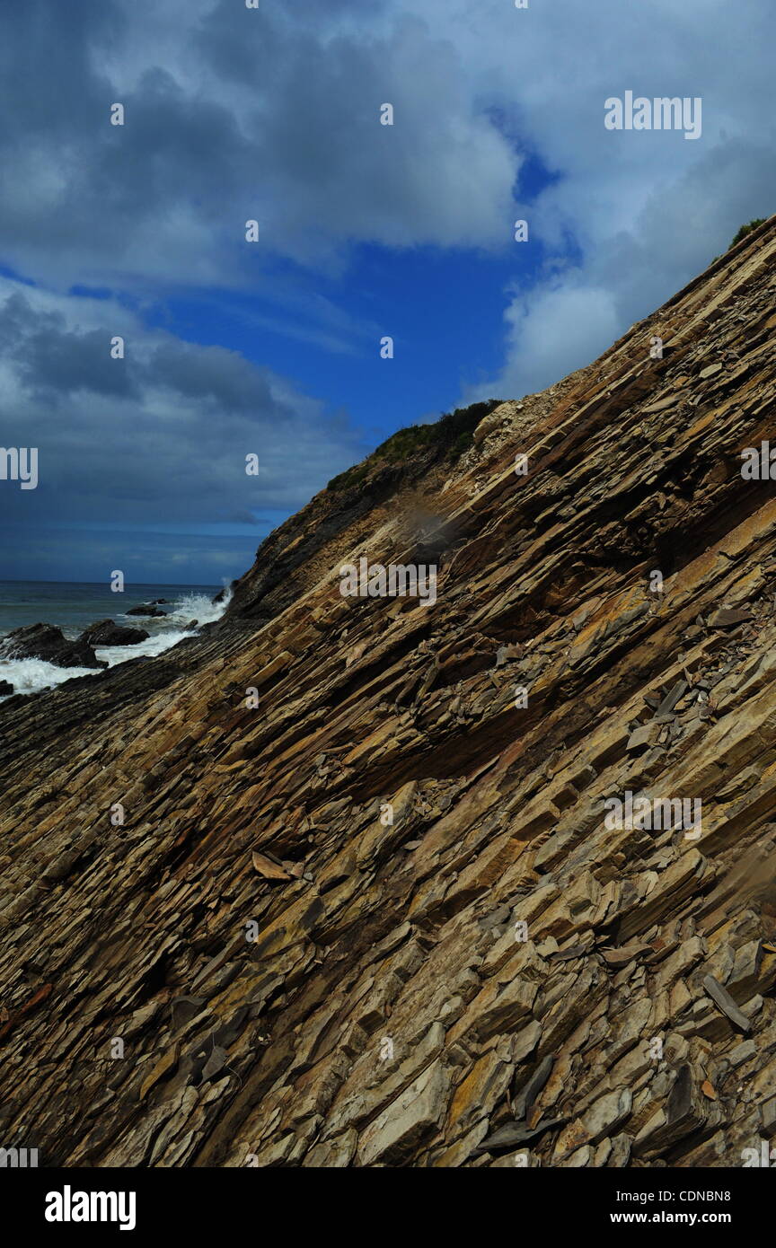 The surf breaks against the granite and shale rocks below the cliffs at ...