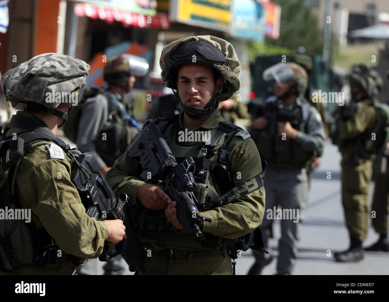 Israeli border guards stand guard near Palestinian civilians during a ...