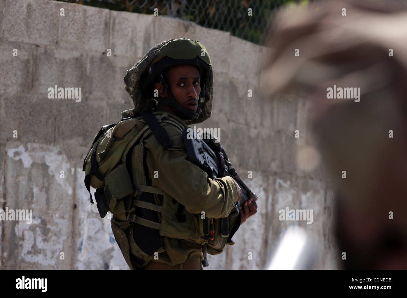 Israeli border guards stand guard near Palestinian civilians during a ...