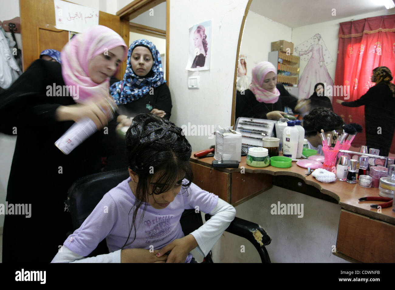 A Palestinian woman applies makeup on the face of a girl during a ...