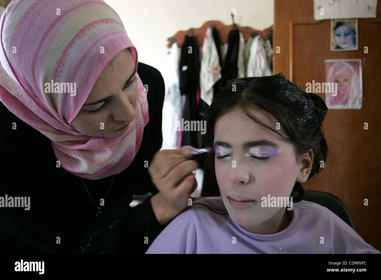 A Palestinian woman applies makeup on the face of a girl during a ...