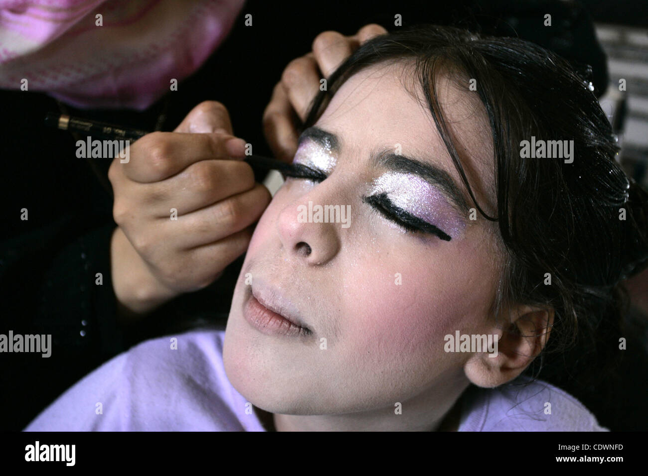 A Palestinian woman applies makeup on the face of a girl during a ...