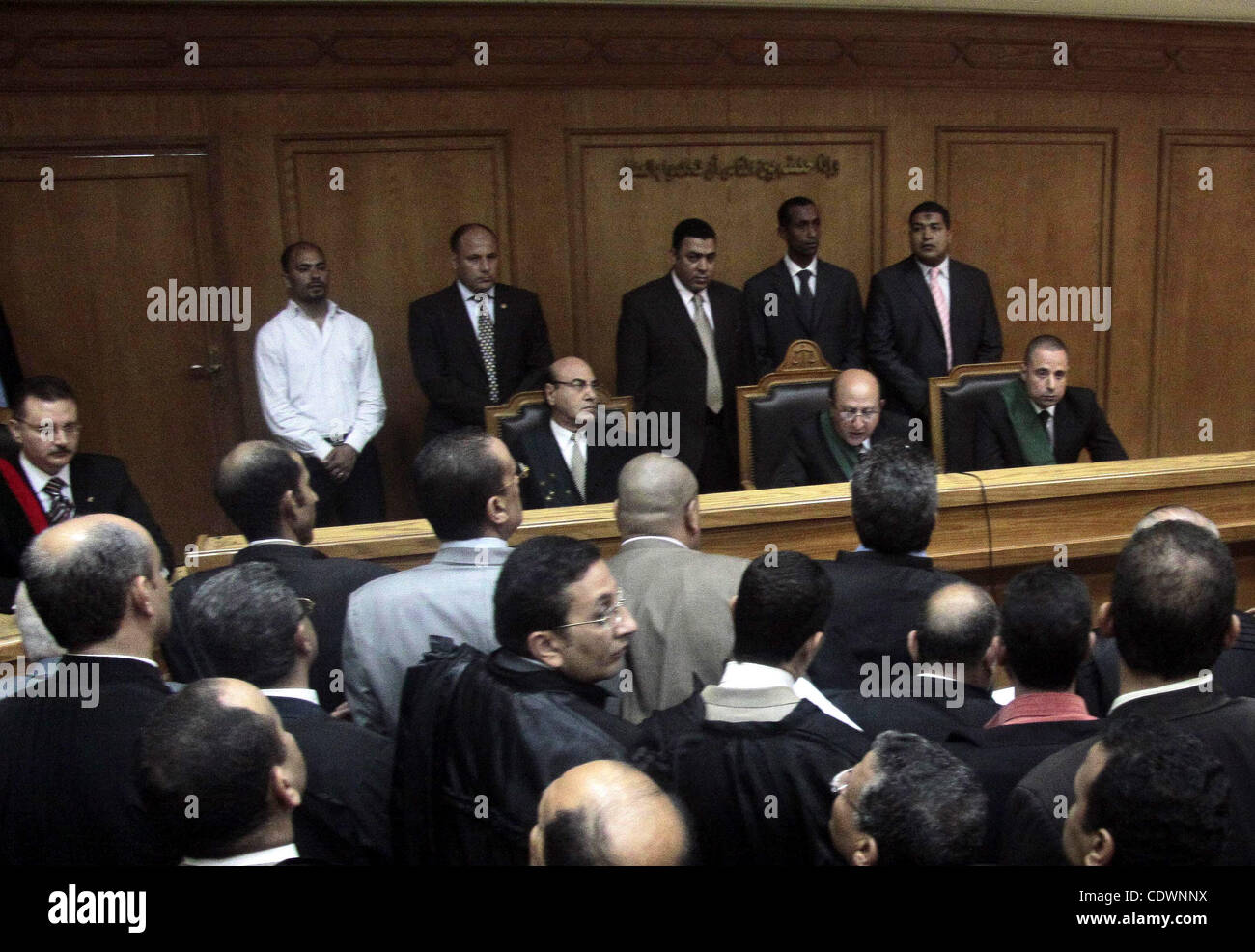 Journalists and bodyguards stand in the Cairo court room as defendants ...
