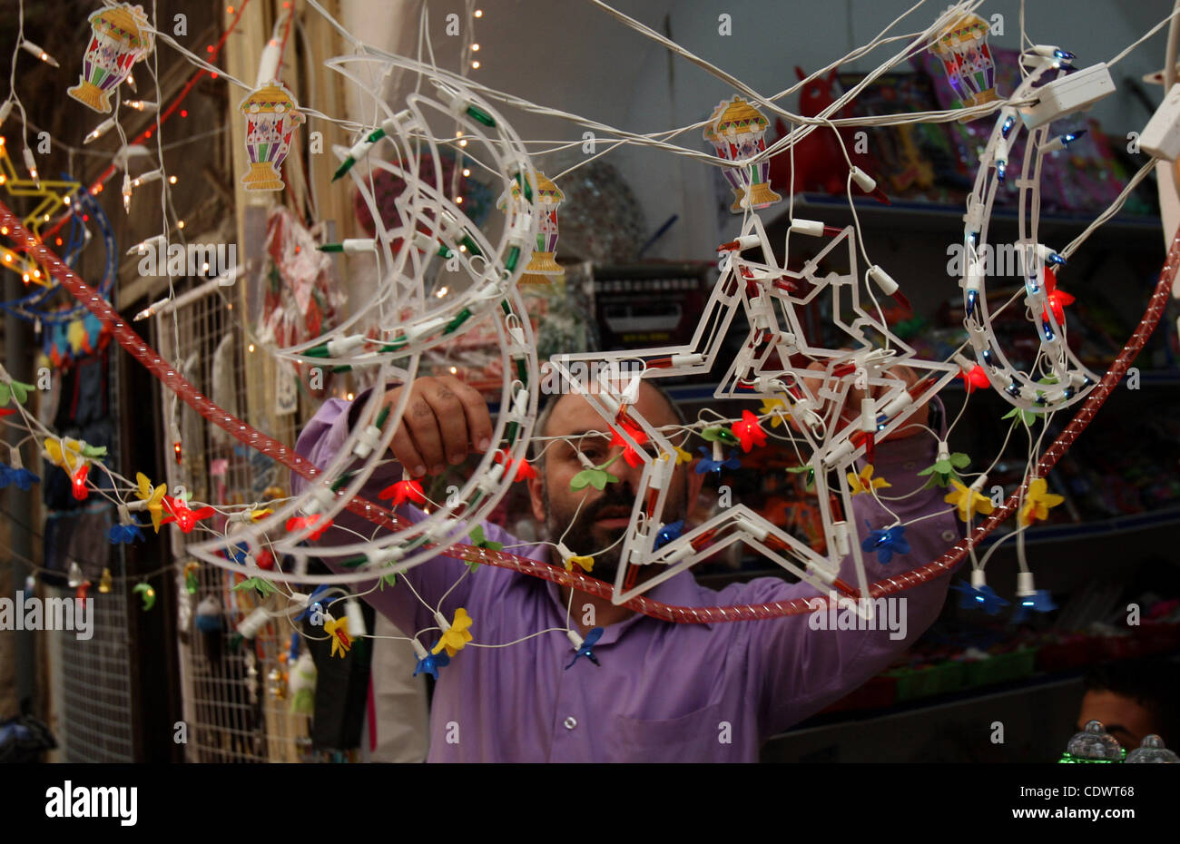 Palestinian vendor stand next to a shop, decorated with Ramadan festive ...