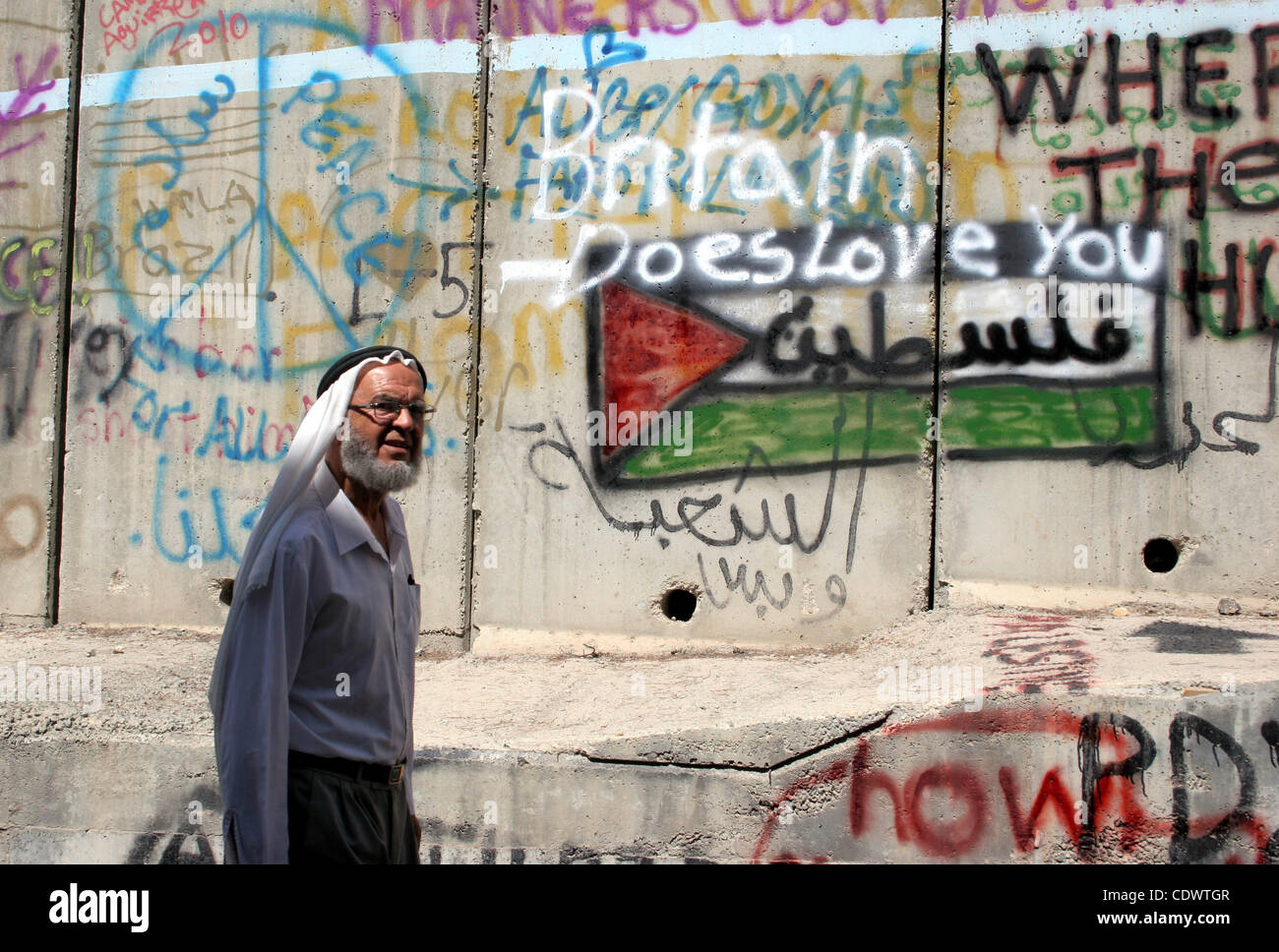 A Palestinian man walks past a mural painted on a section of the ...