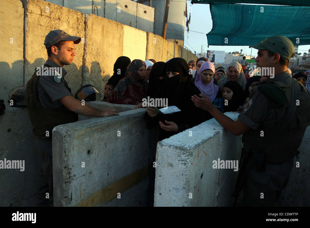 Palestinian women wait in line to pass through the Kalandia checkpoint ...