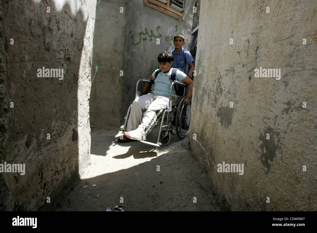 A Palestinian boy sits on a chair disabled in front of his home at the ...
