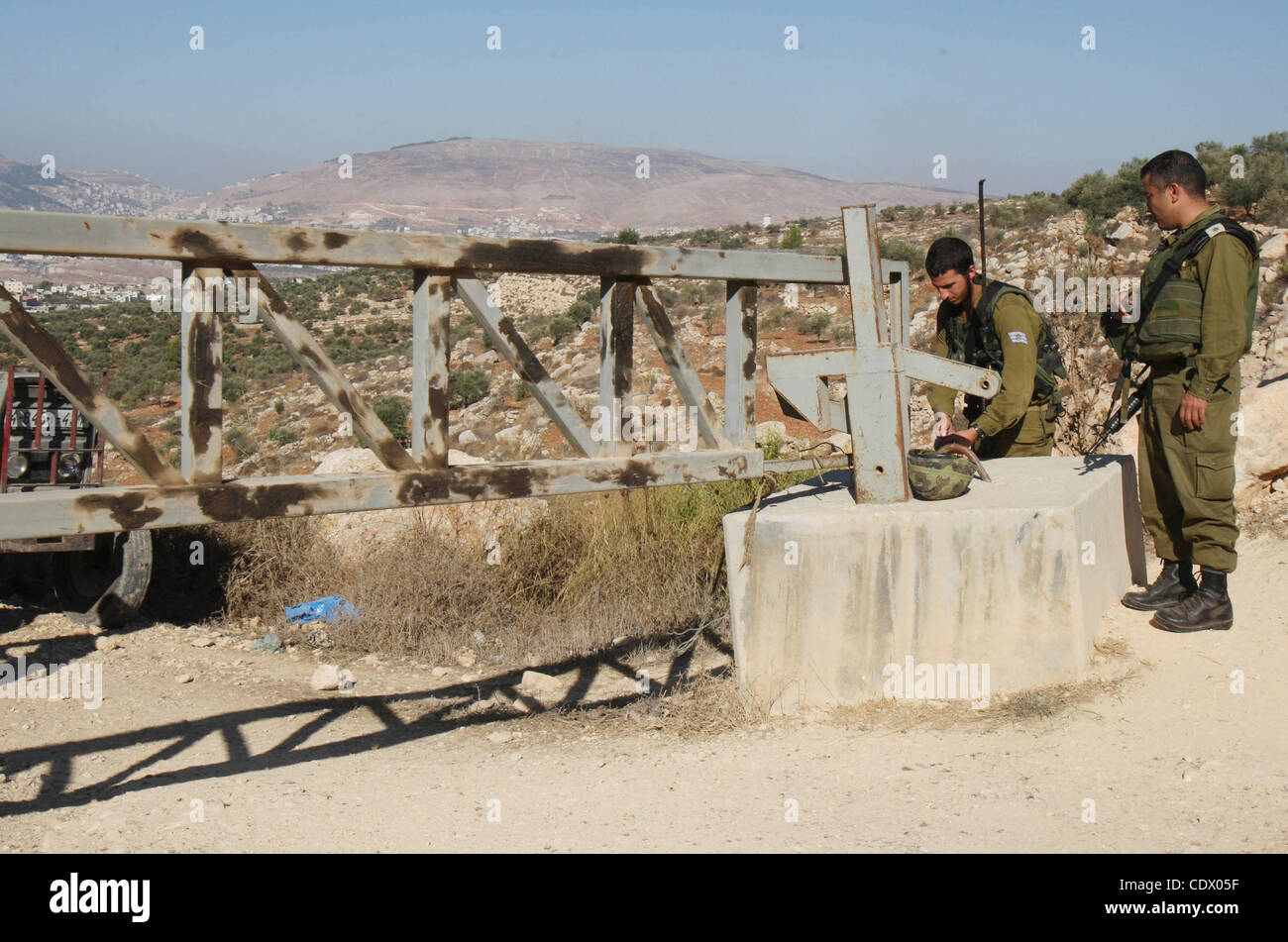 Israeli soldiers stand guard at a barrier erected on Palestinian land ...