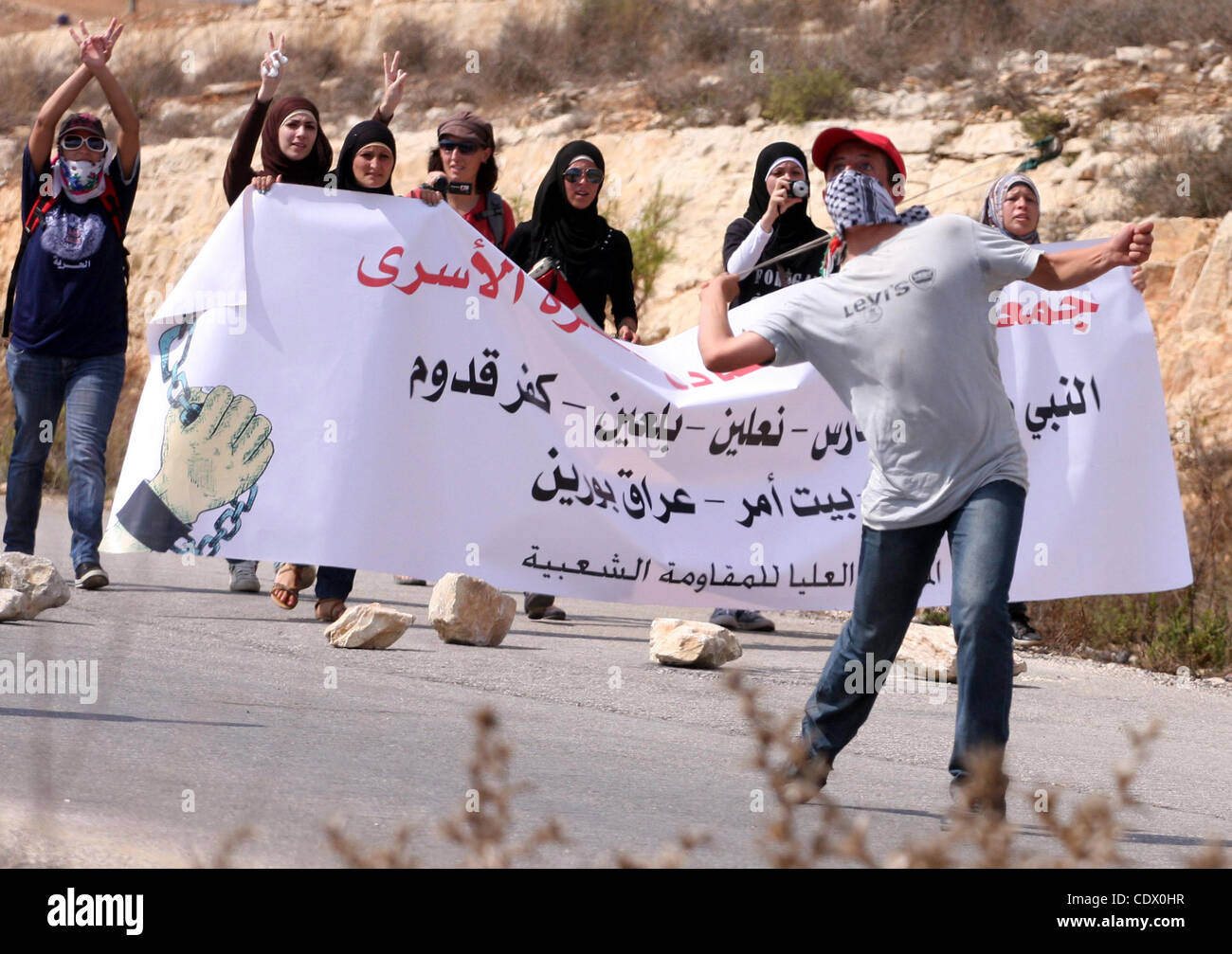 A Palestinian youth uses a sling to hurl stones towards Israeli ...