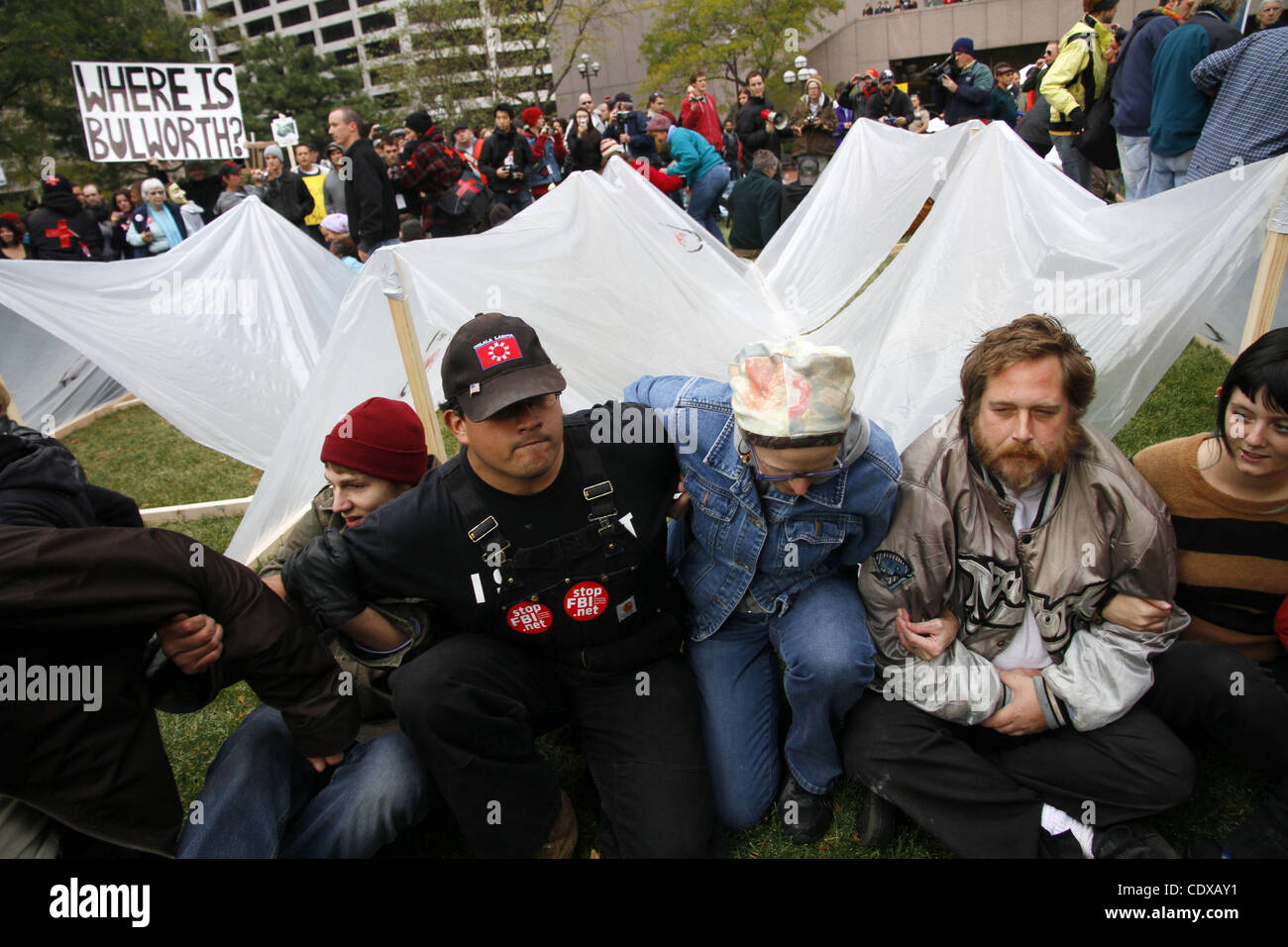 Civil disobedience protesters lock arms around a set of clear tents ...