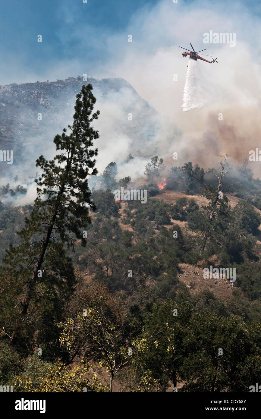 A Sikorski firefighting helicopter drops water on the fire's front at ...
