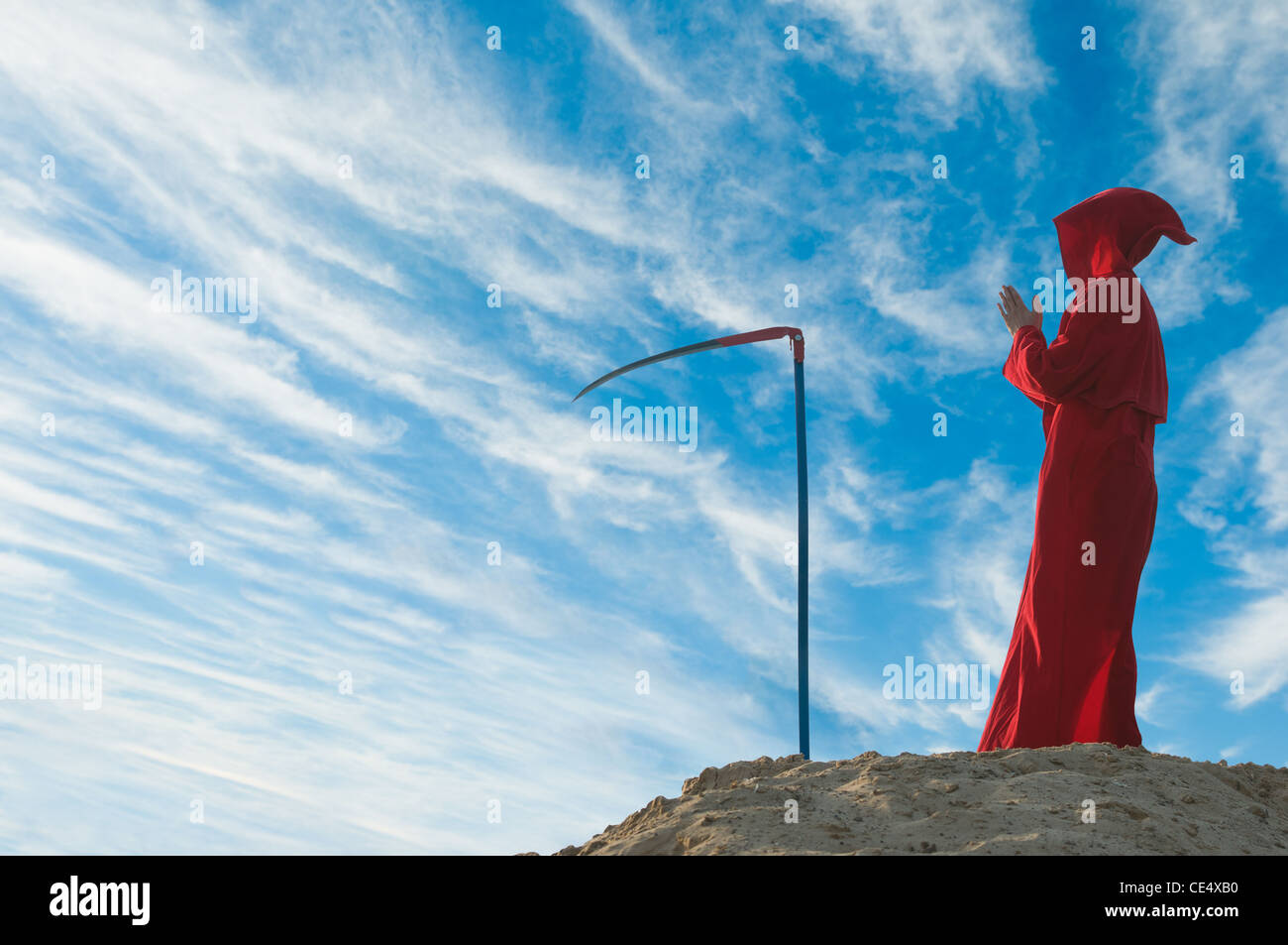 Spooky figure in red cloak with scythe Stock Photo - Alamy