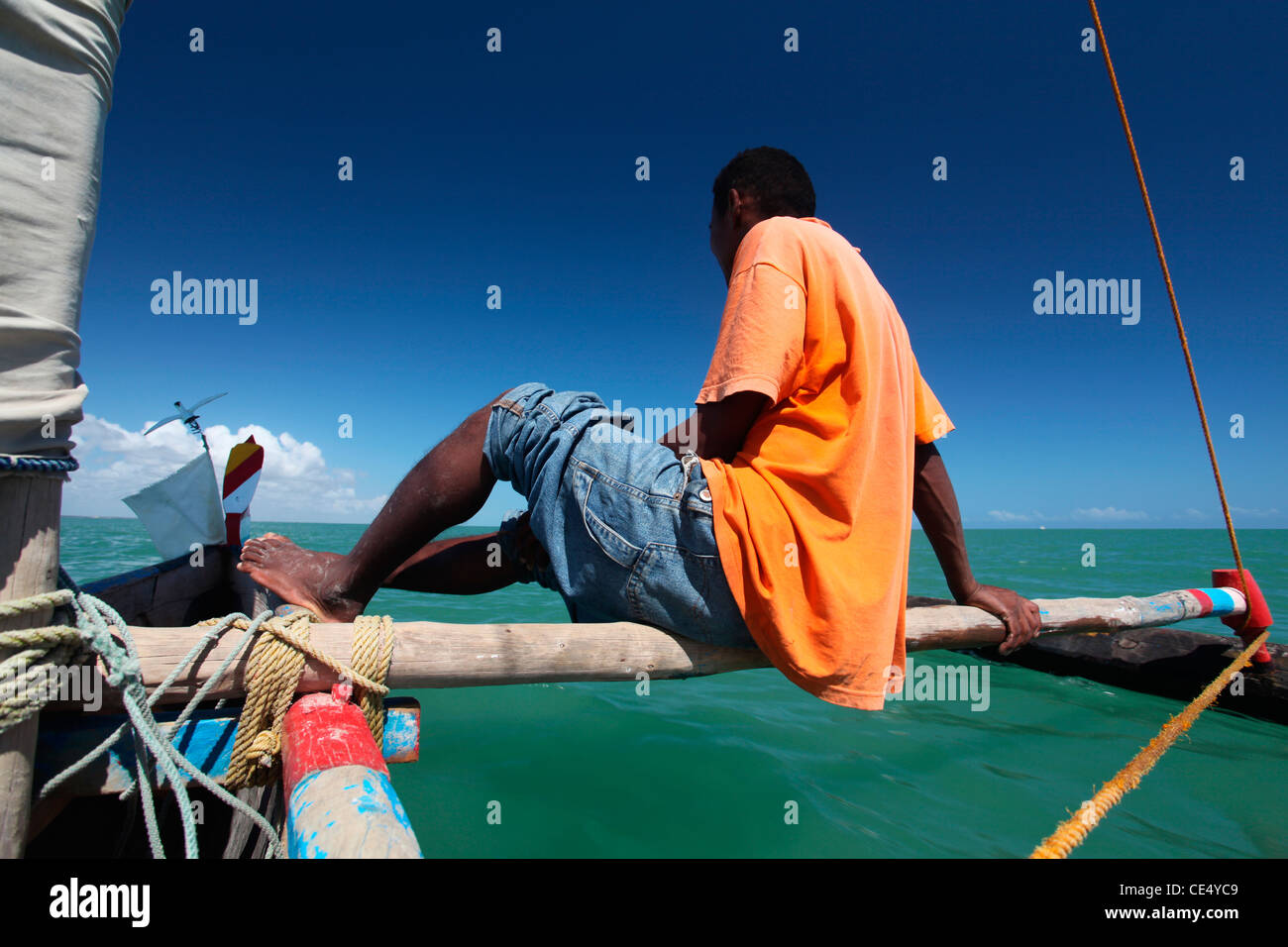 A fisherman sitting on a typical malagasy sailing pirogue, or dugout ...