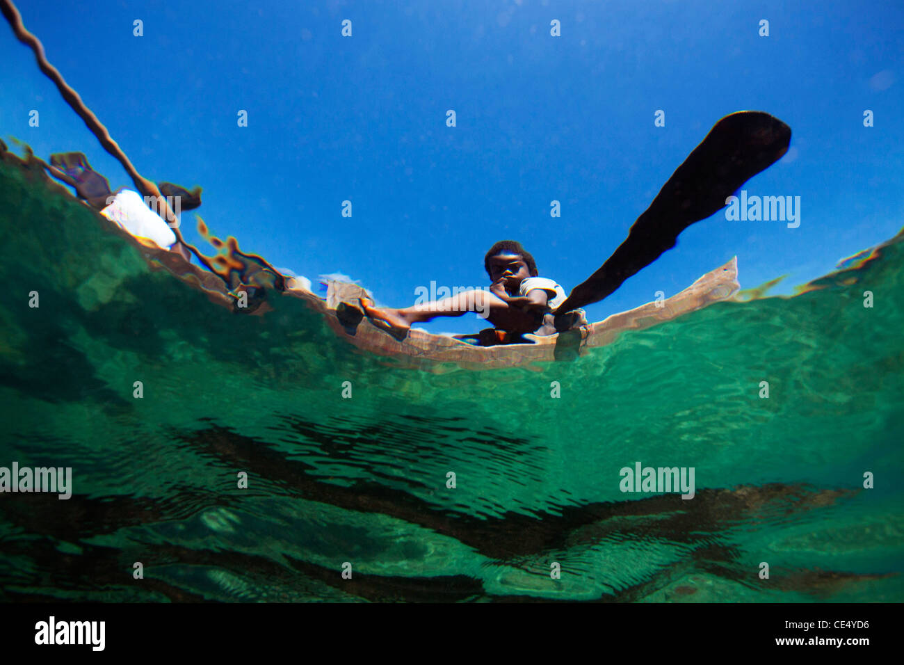 Underwater view of a malagasy boy rowing his pirogue, or outrigger ...