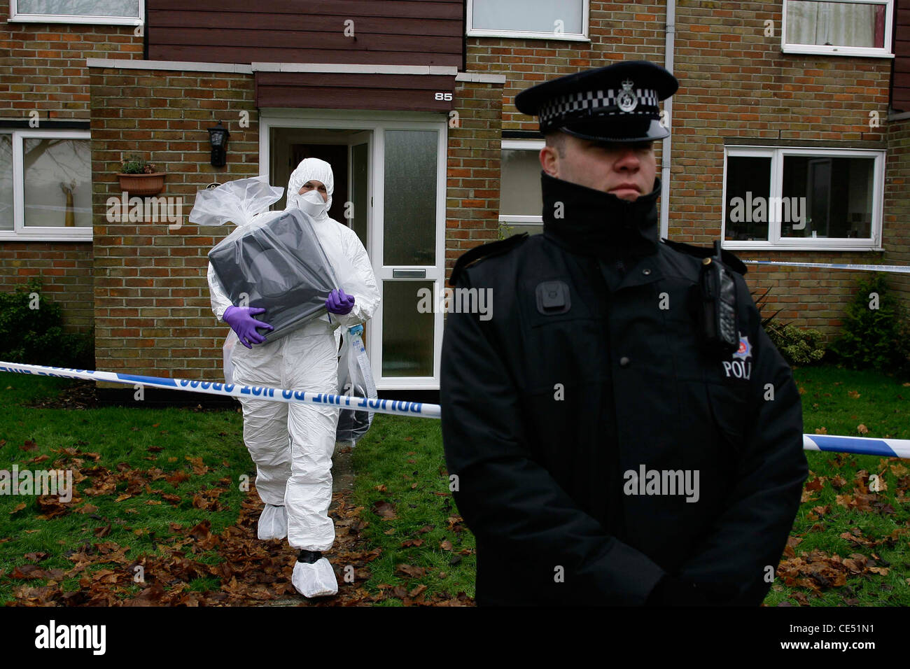 Scene Of Crime Officers remove a computer from a crime scene as a ...