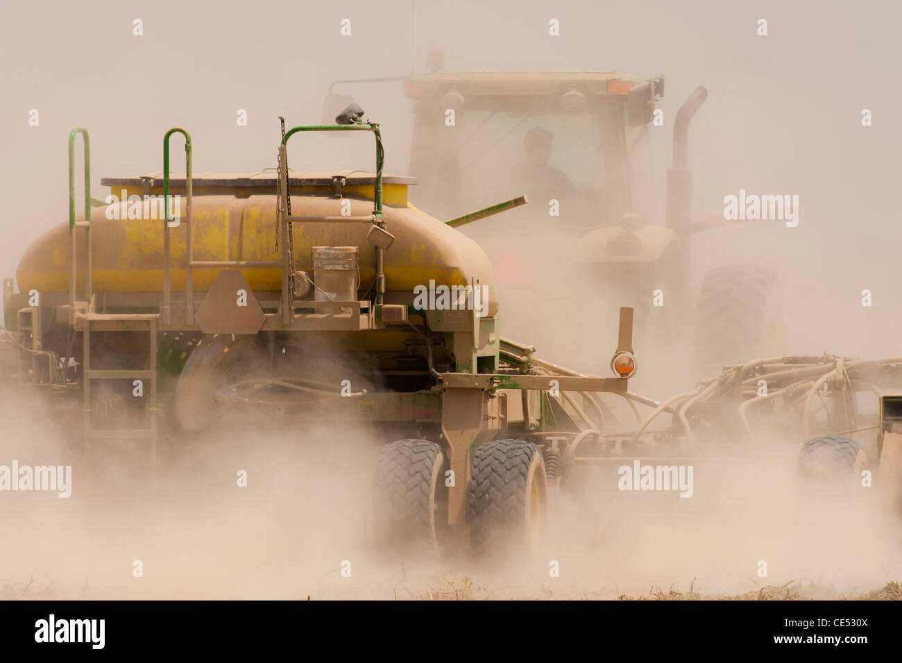Tractor in cloud of dust while performing chemical application on dusty ...