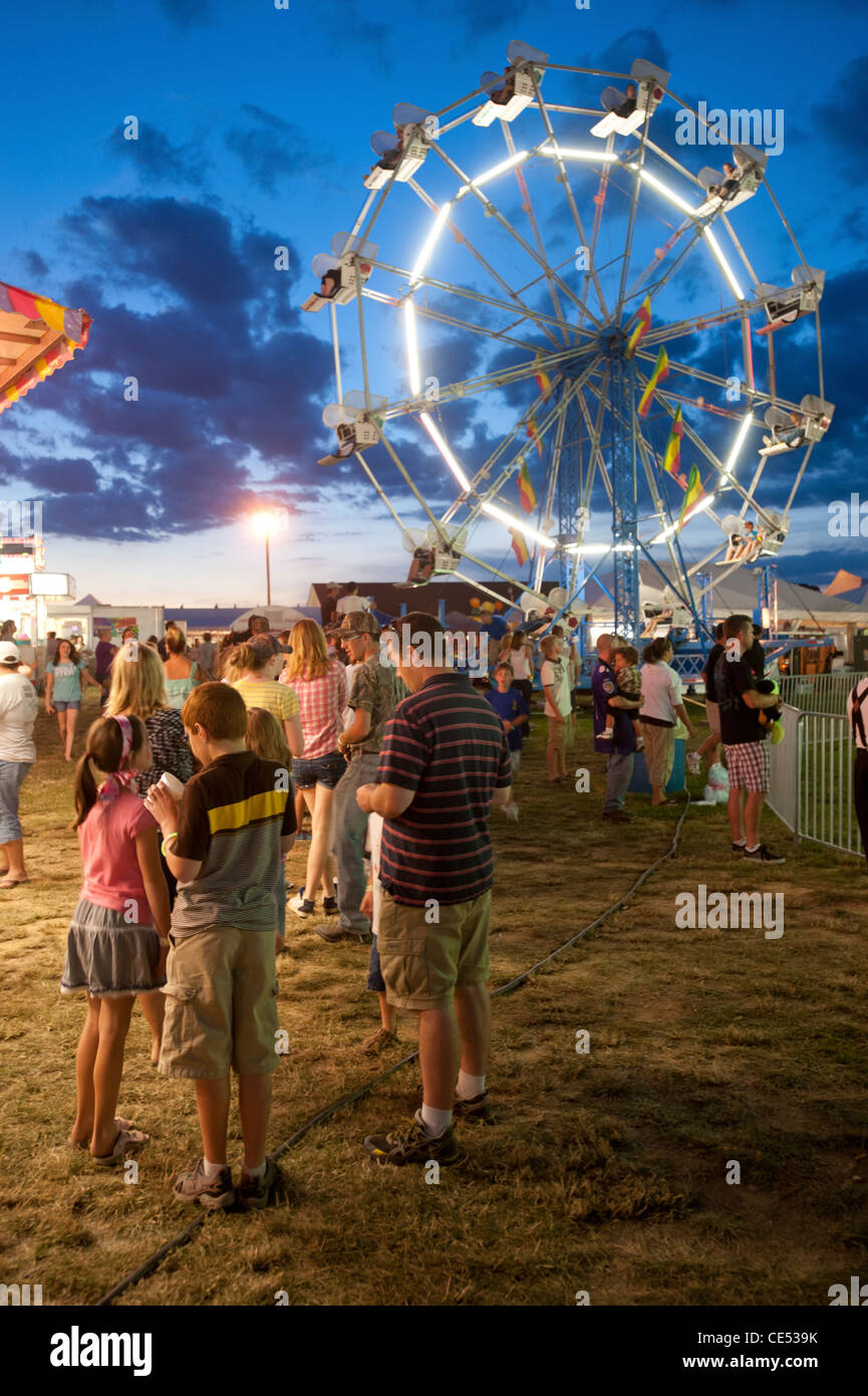 A line of people waiting for ferris wheel and lights in motion of ride ...