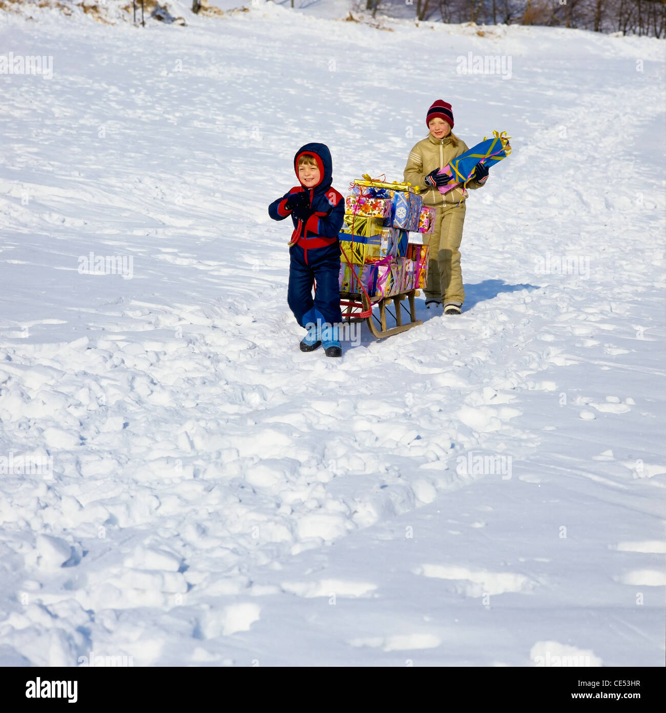 Little boy pulling a sledge loaded with Christmas presents, girl ...