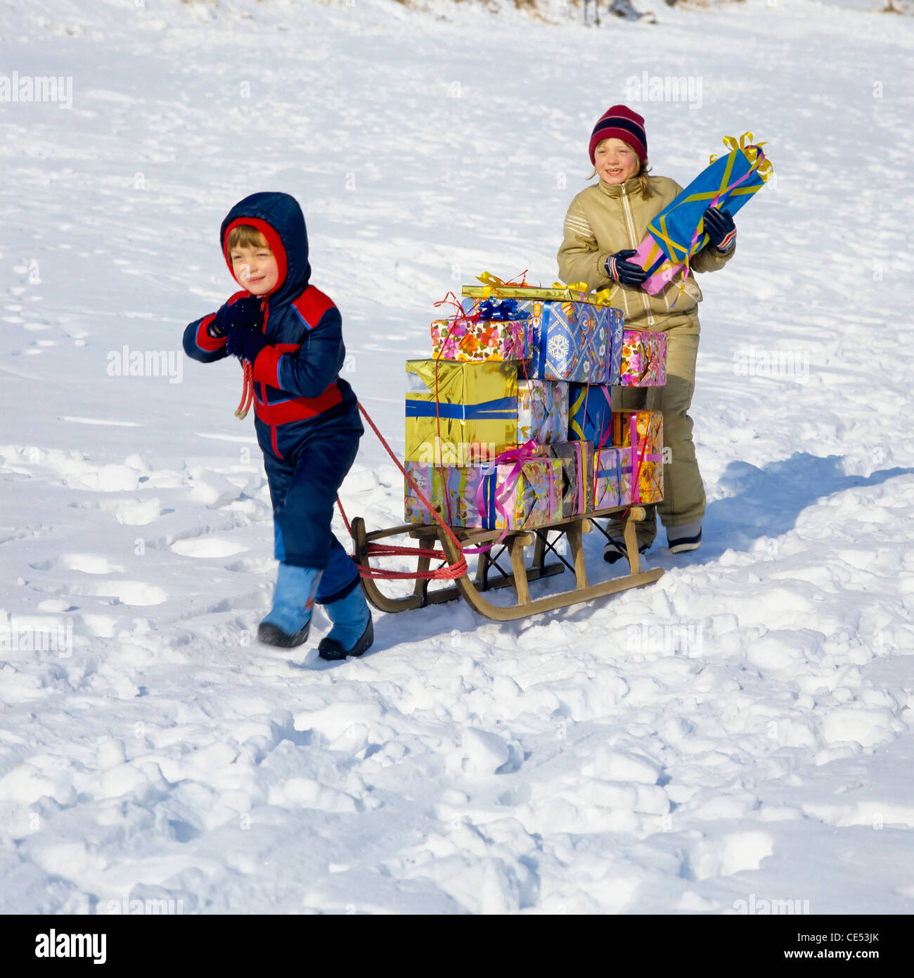 Little boy pulling a sledge loaded with Christmas presents, girl ...