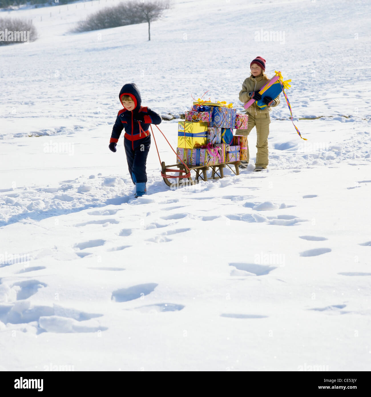 Little boy pulling a sledge loaded with Christmas presents, girl ...