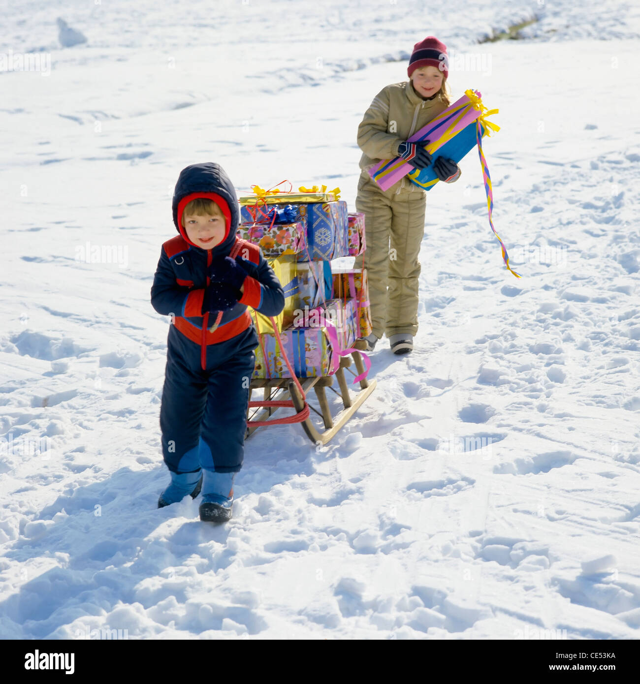 Little boy pulling a sledge loaded with Christmas presents, girl ...