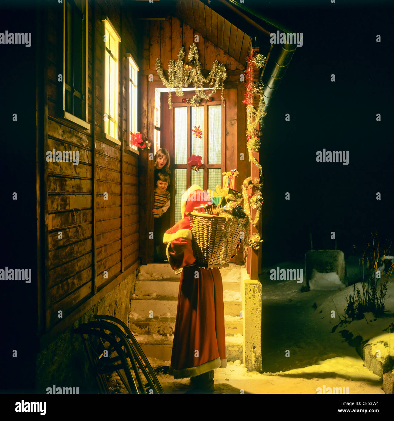 Surprised children at cottage doorway watching Santa Claus arrival ...