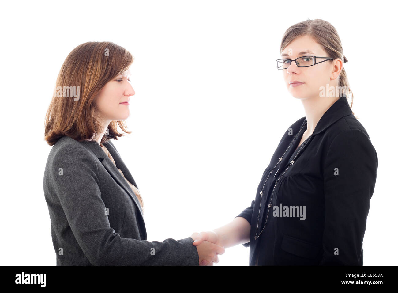 Two young serious business women handshaking, isolated on white ...