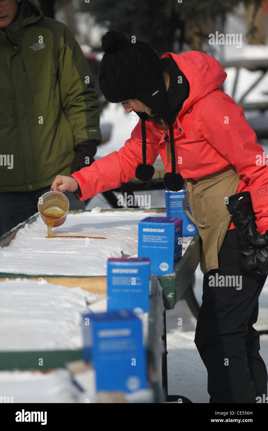 Female pouring maple syrup in snow for a sugar on snow party Stock ...