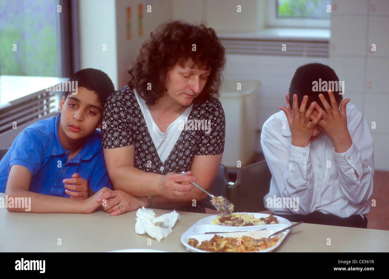 Autistic pupils at a special school receiving assistance at lunchtime ...