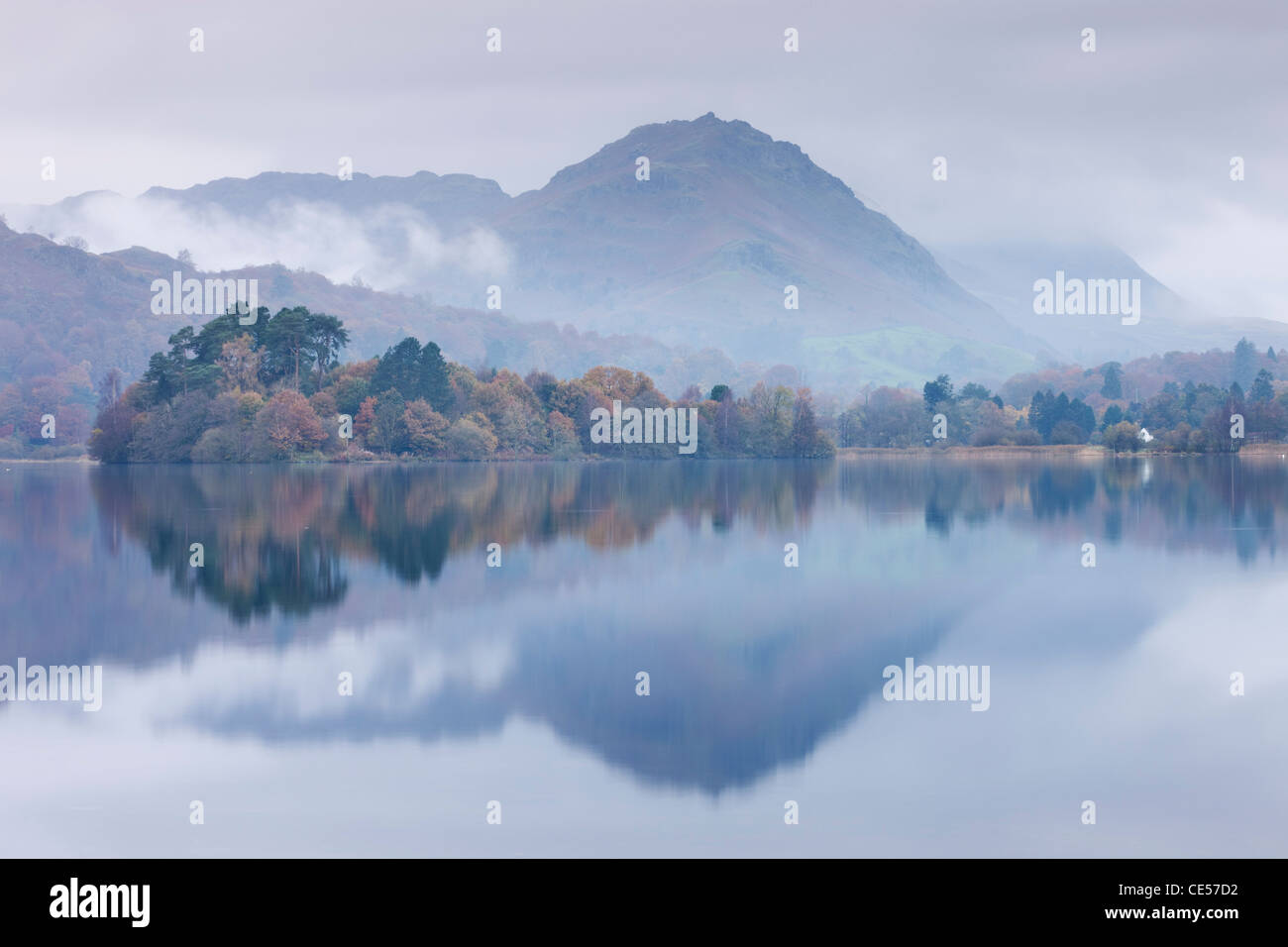 Mist hangs over the lake and island at Grasmere with Helm Crag beyond ...