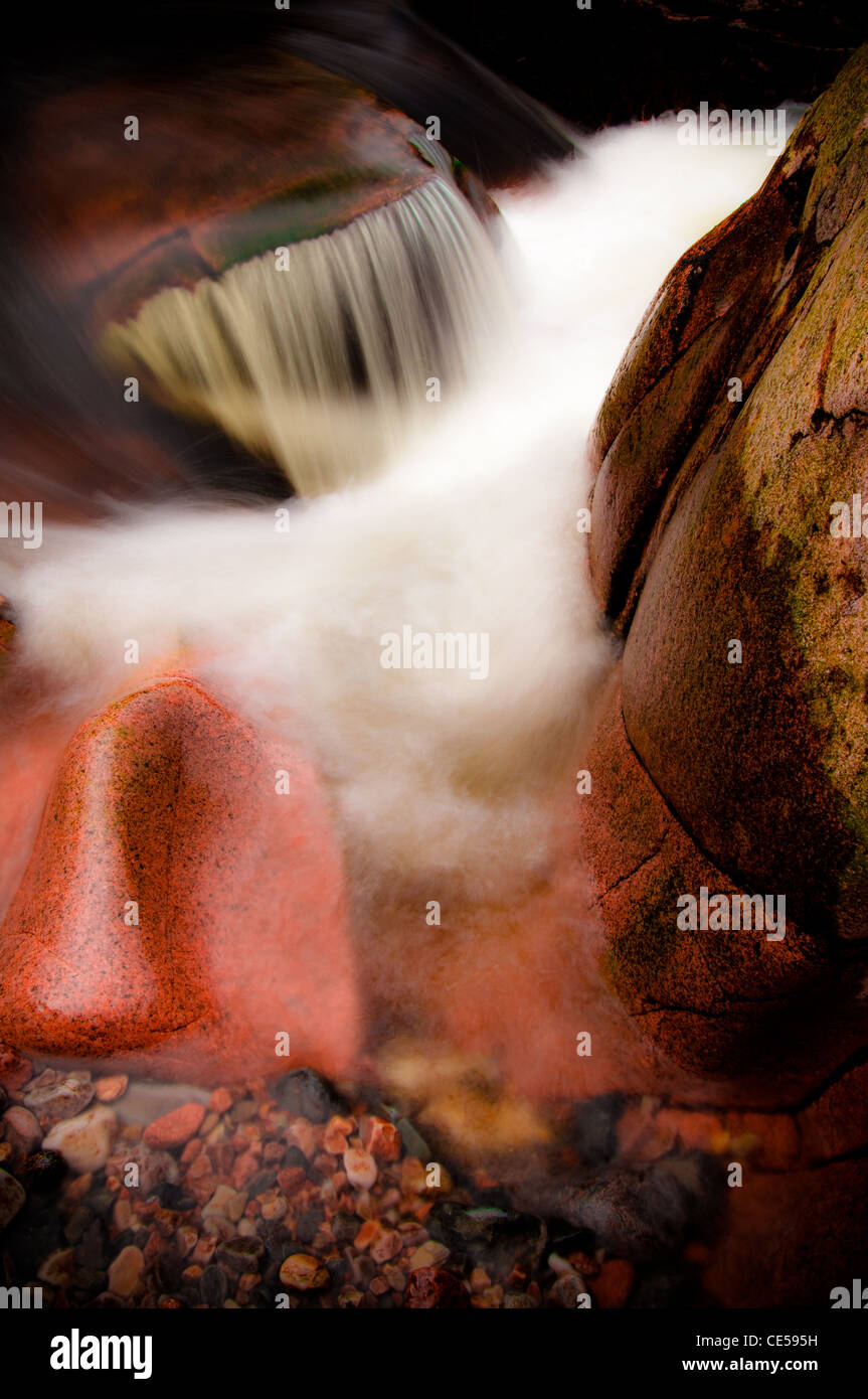 Long exposure of the river Nevis.Water rushes over the colorful rocks ...