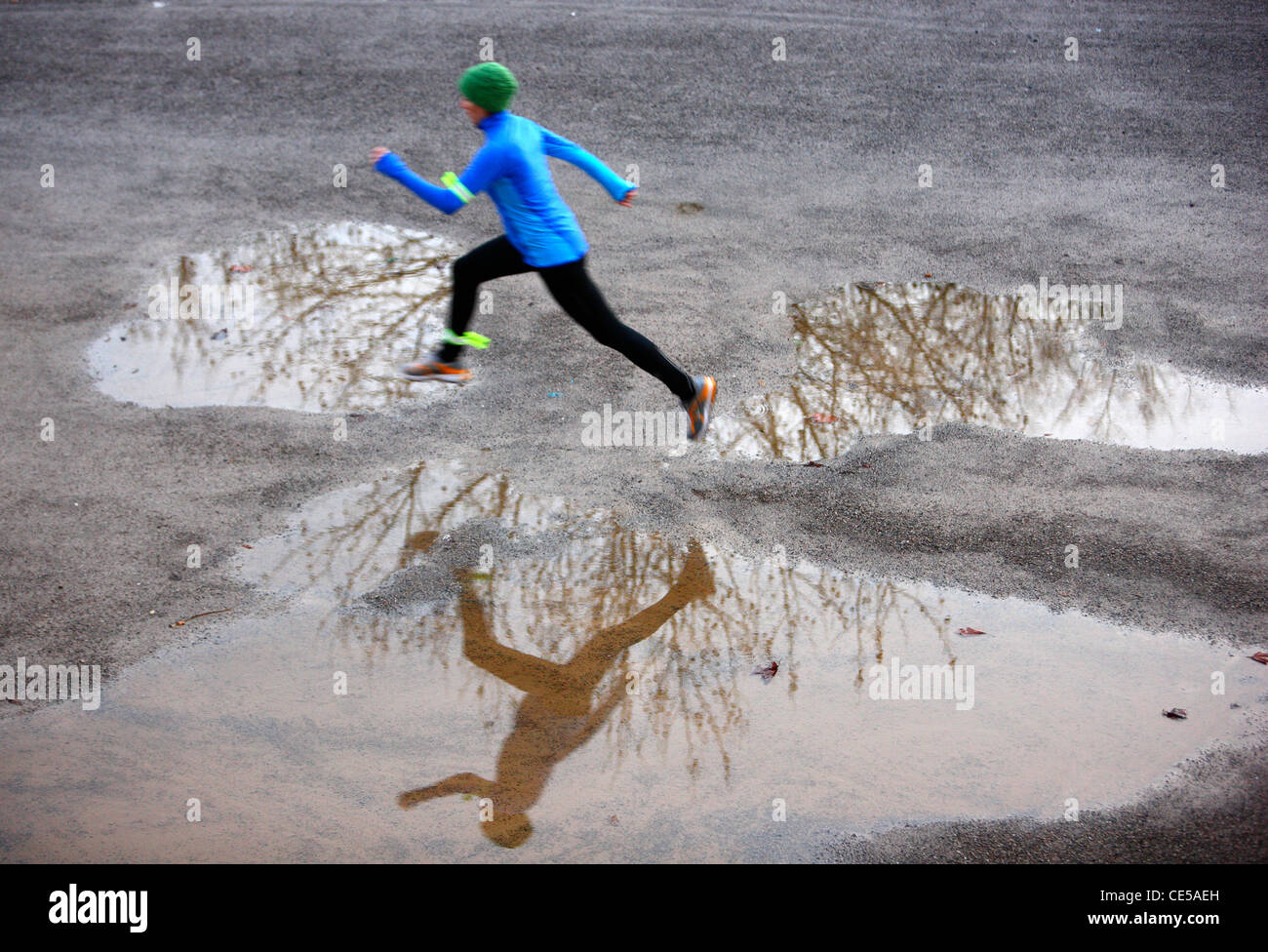 2 young women running in winter, jumping over wet spots on the way ...