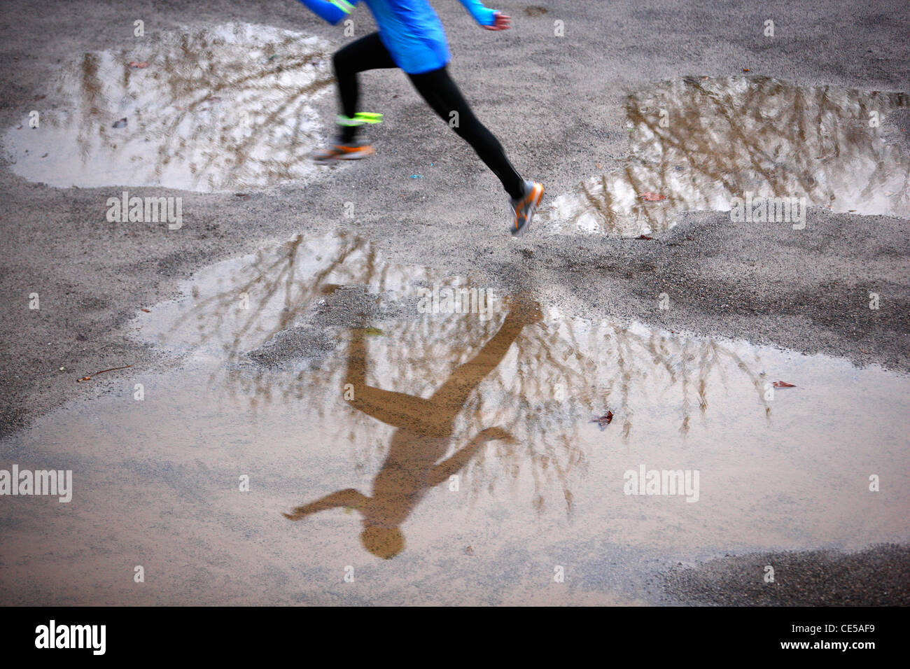 2 young women running in winter, jumping over wet spots on the way ...