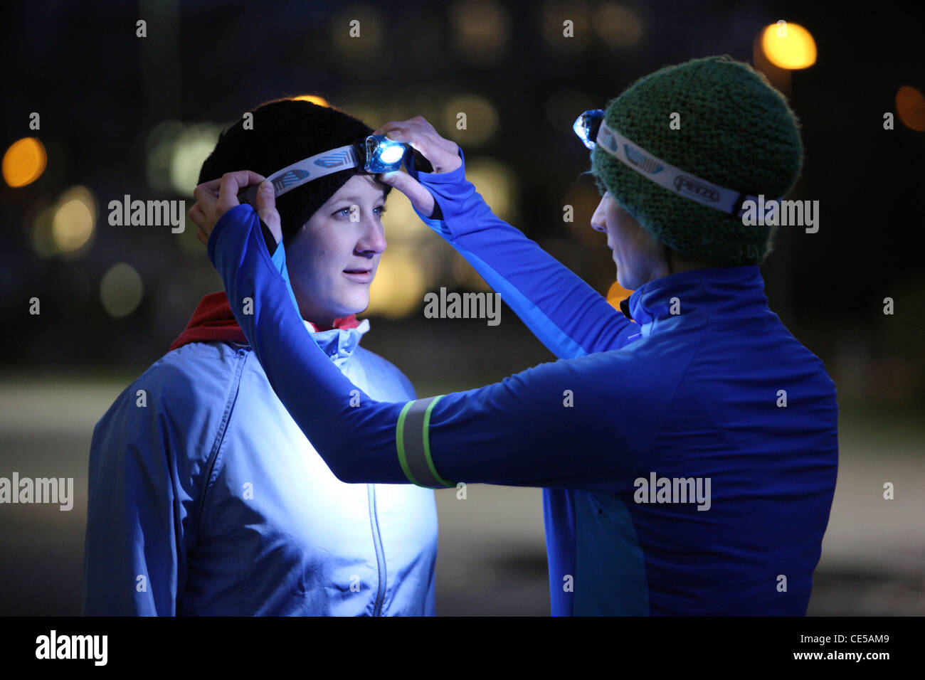 Two young women jogging at night in winter, fall. With headlamps in the ...