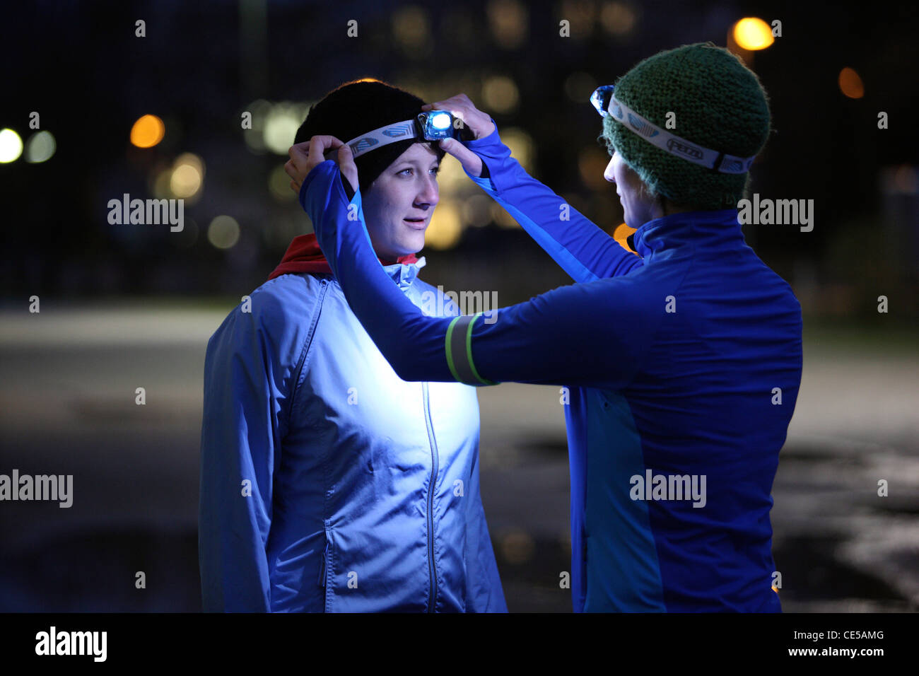 Two young women jogging at night in winter, fall. With headlamps in the ...