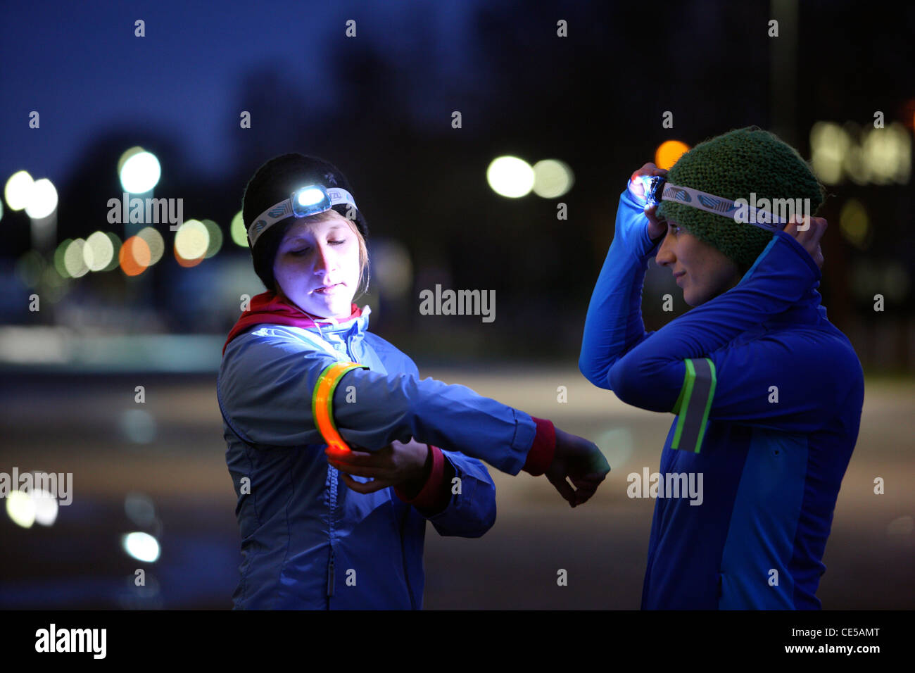 Two young women jogging at night in winter, fall. With headlamps in the ...