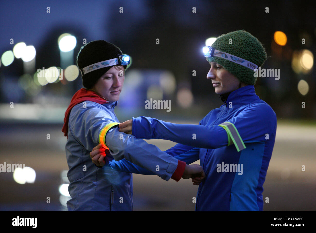 Two young women jogging at night in winter, fall. With headlamps in the ...