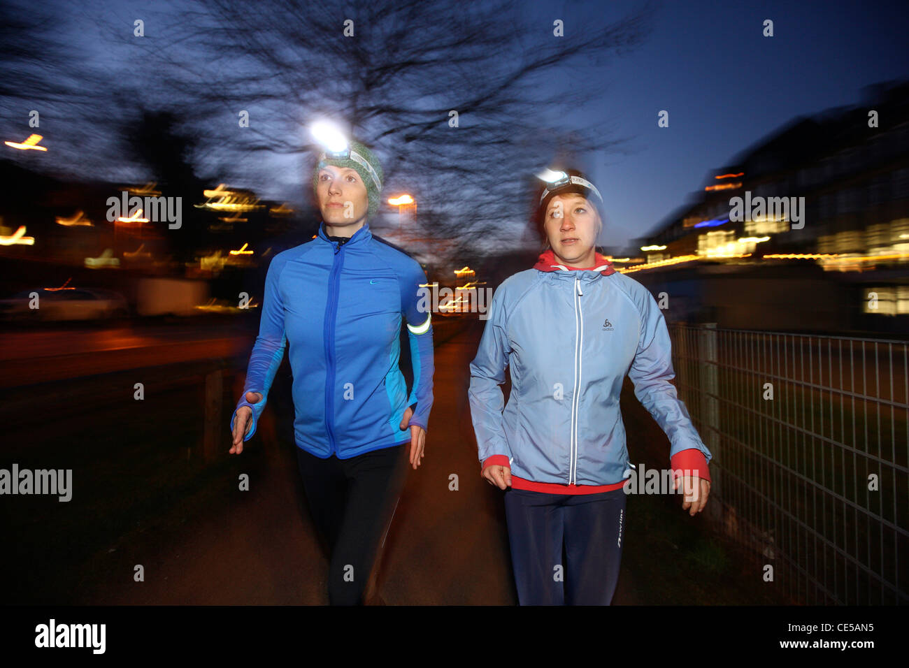 Two young women jogging at night in winter, fall. With headlamps in the ...