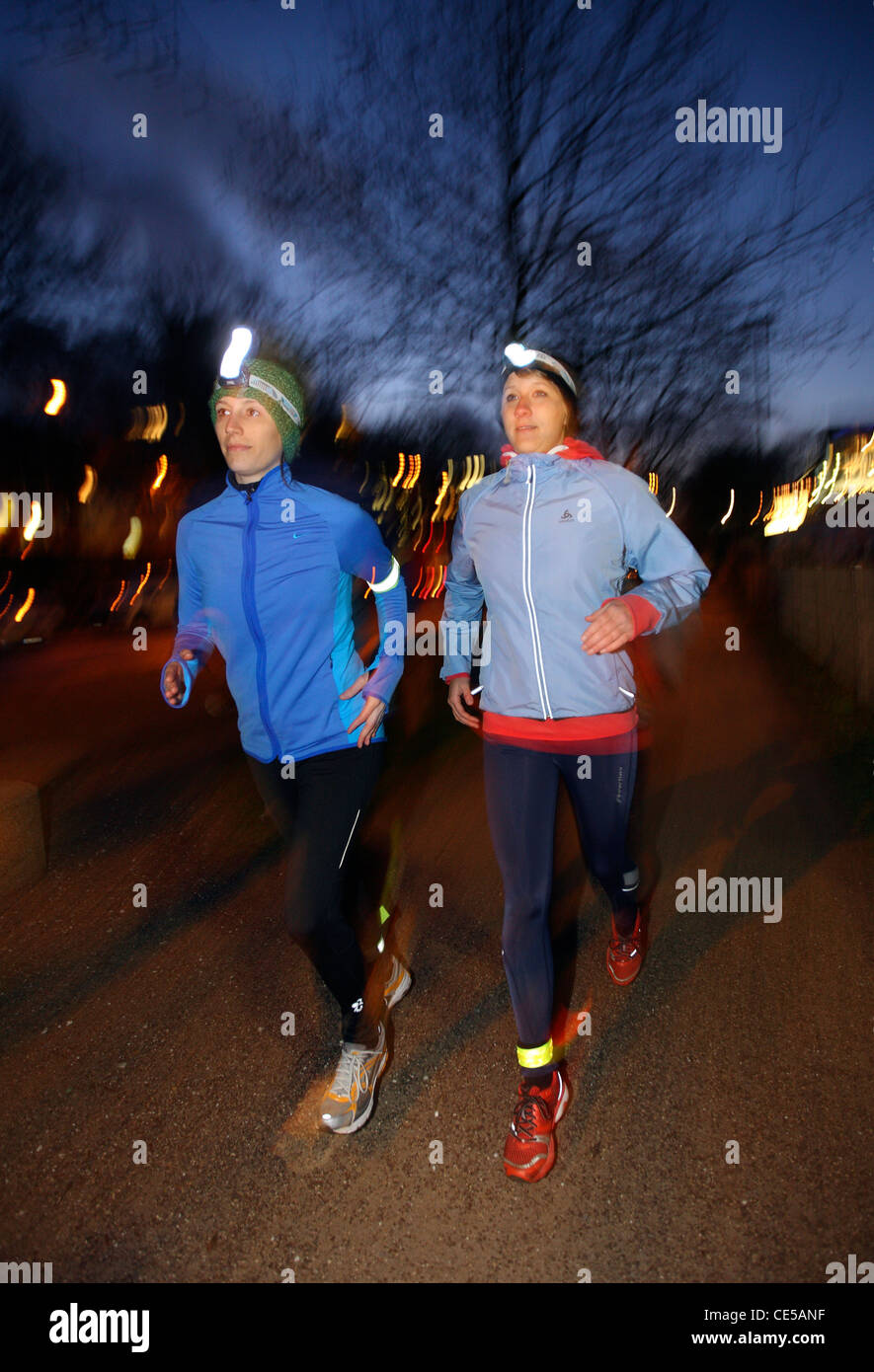 Two young women jogging at night in winter, fall. With headlamps in the ...