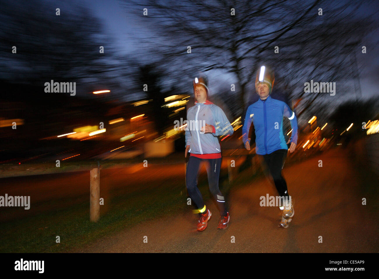 Two young women jogging at night in winter, fall. With headlamps in the ...