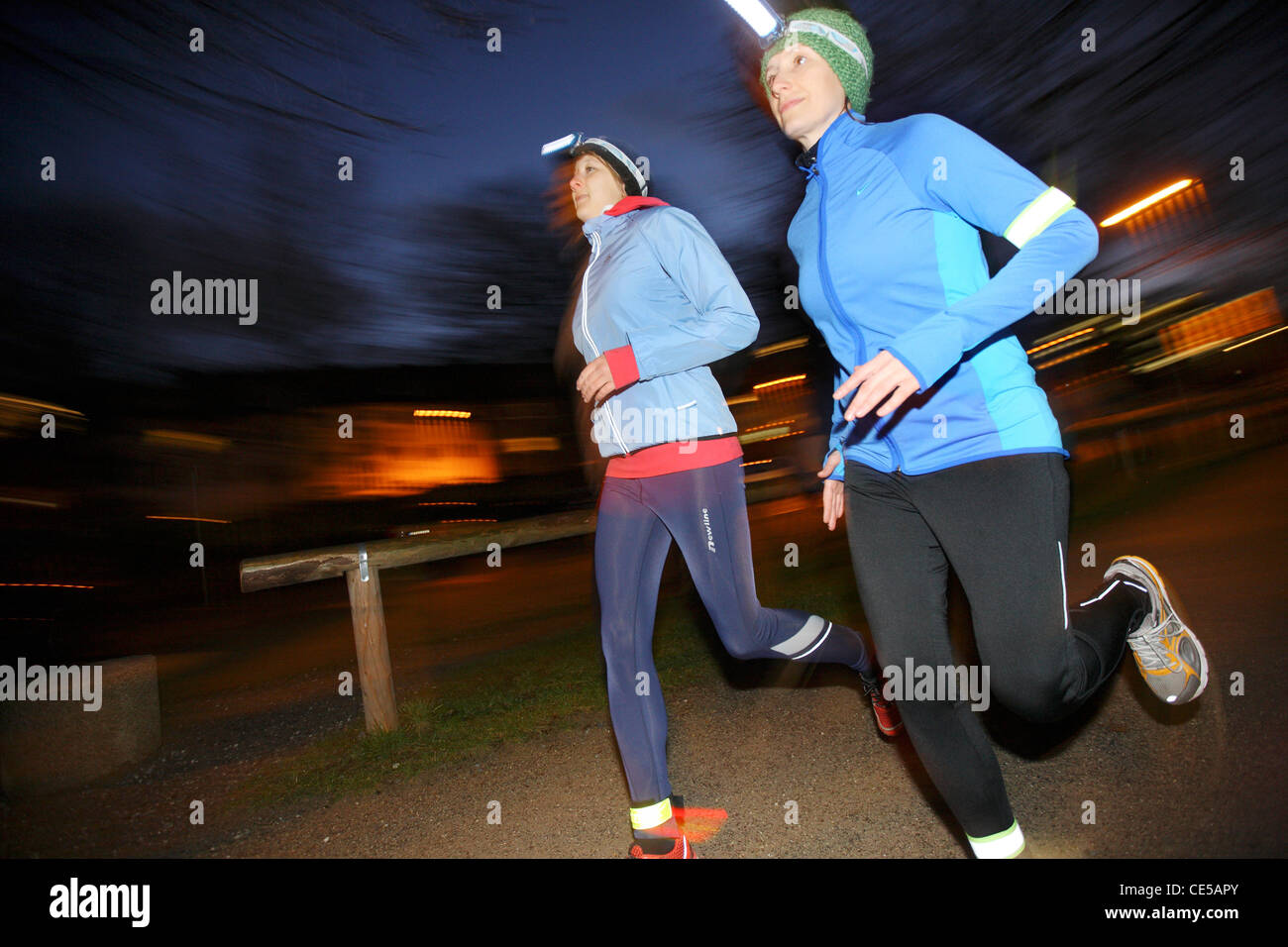 Two young women jogging at night in winter, fall. With headlamps in the ...
