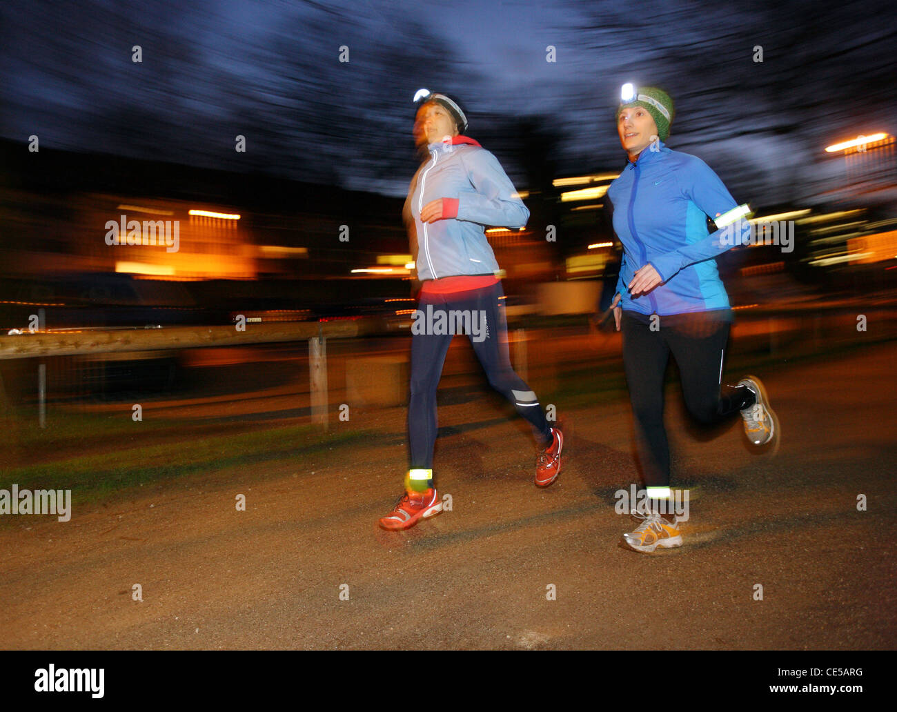 Two young women jogging at night in winter, fall. With headlamps in the ...