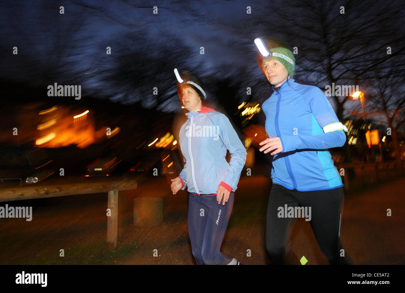 Two young women jogging at night in winter, fall. With headlamps in the ...