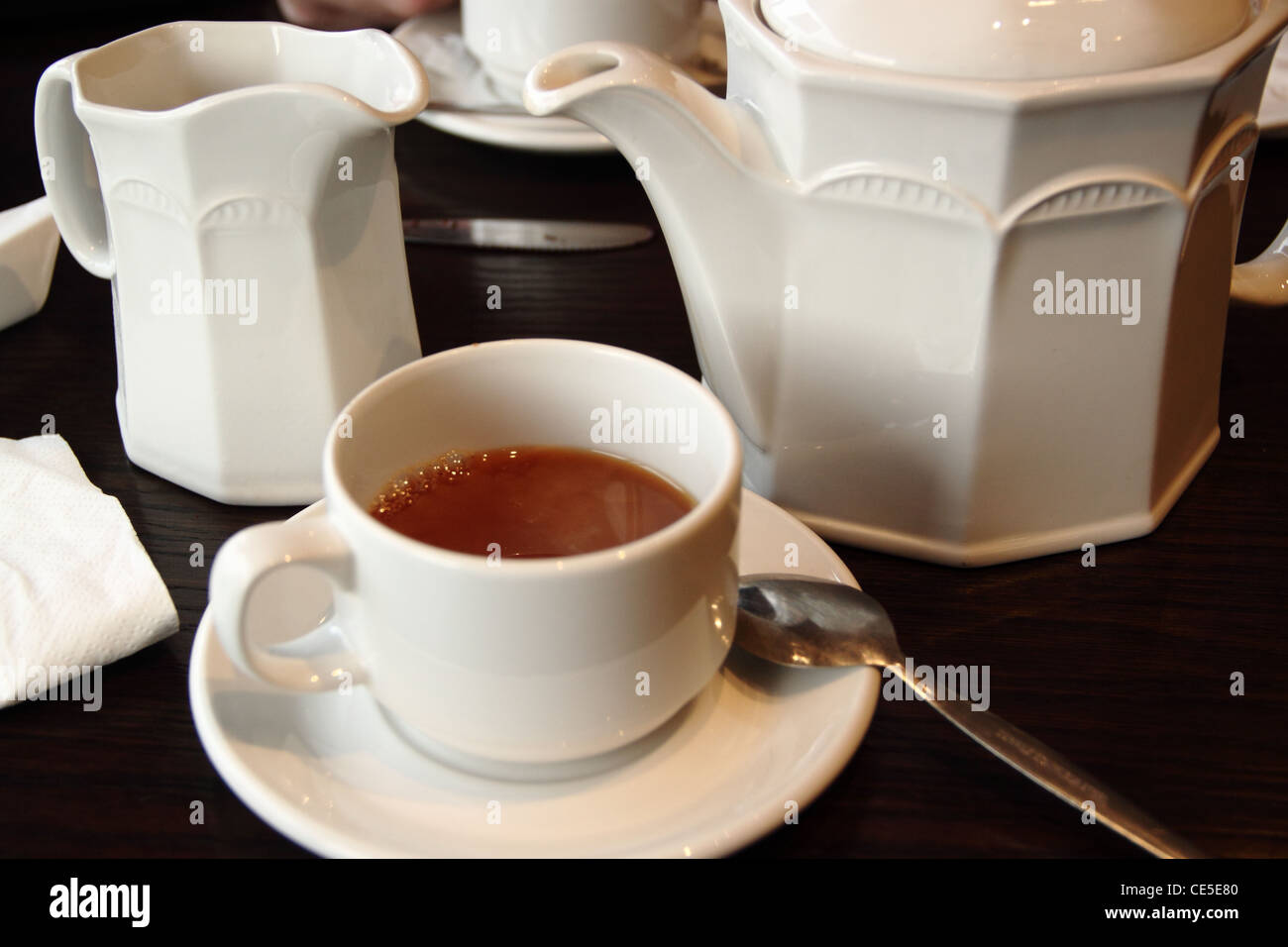 A cup of tea with a splash of milk and a ceramic teapot Stock Photo - Alamy