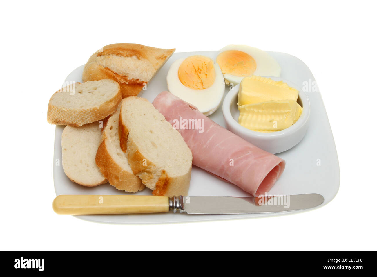 Bread, butter, ham and hard boiled egg with a knife on a plate isolated ...