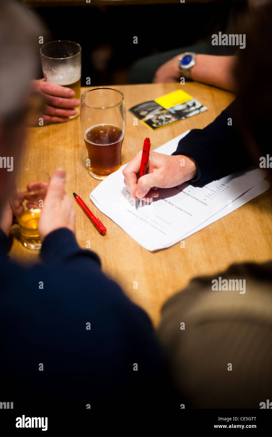 A team of people answering questions competing in a pub quiz in a bar ...