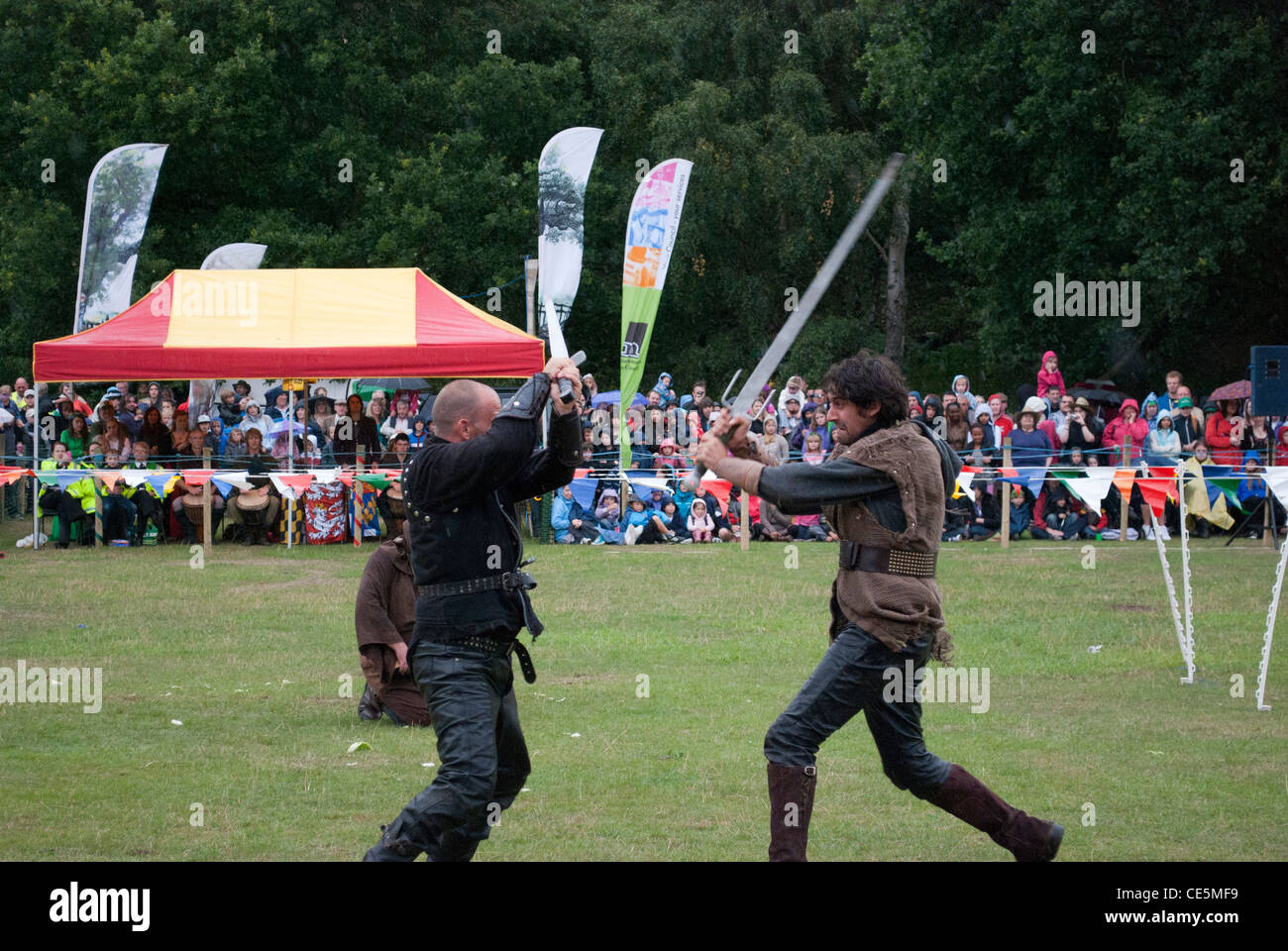 Two men in medieval costume sword fighting at jousting tournament with ...